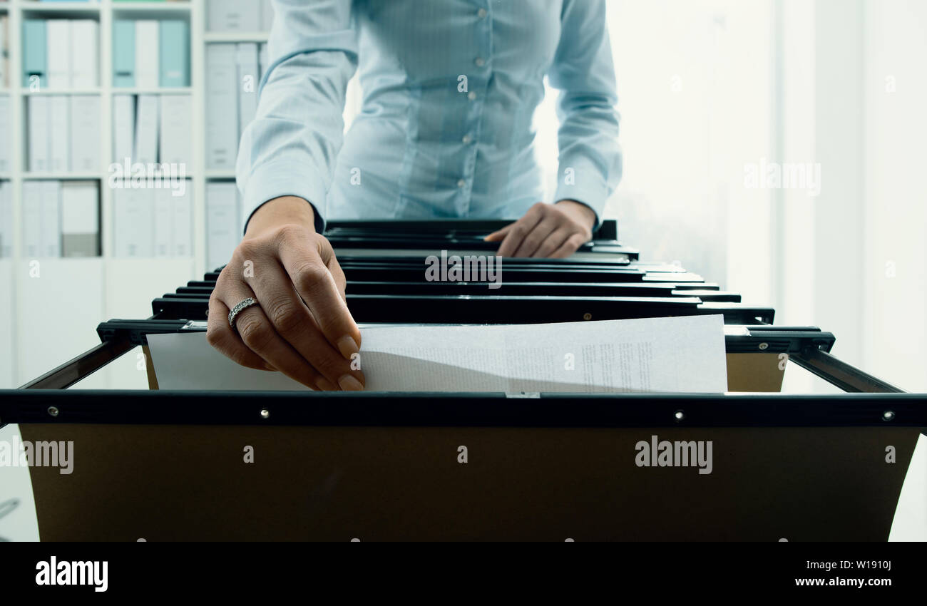Female office worker searching files and paperwork in the archive, she ...