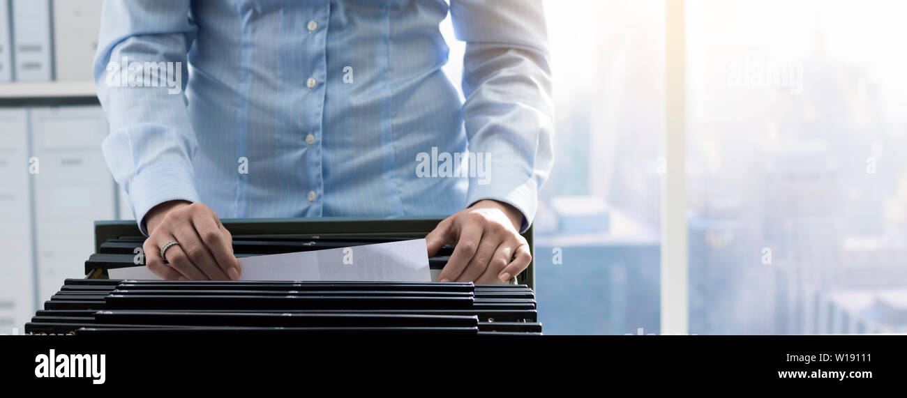 Female office worker searching files and paperwork in the archive, she ...