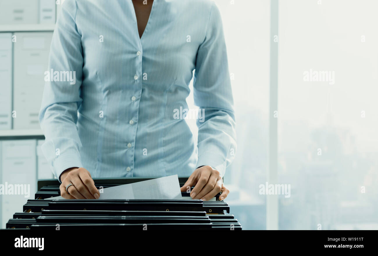 Female office worker searching files and paperwork in the archive, she ...