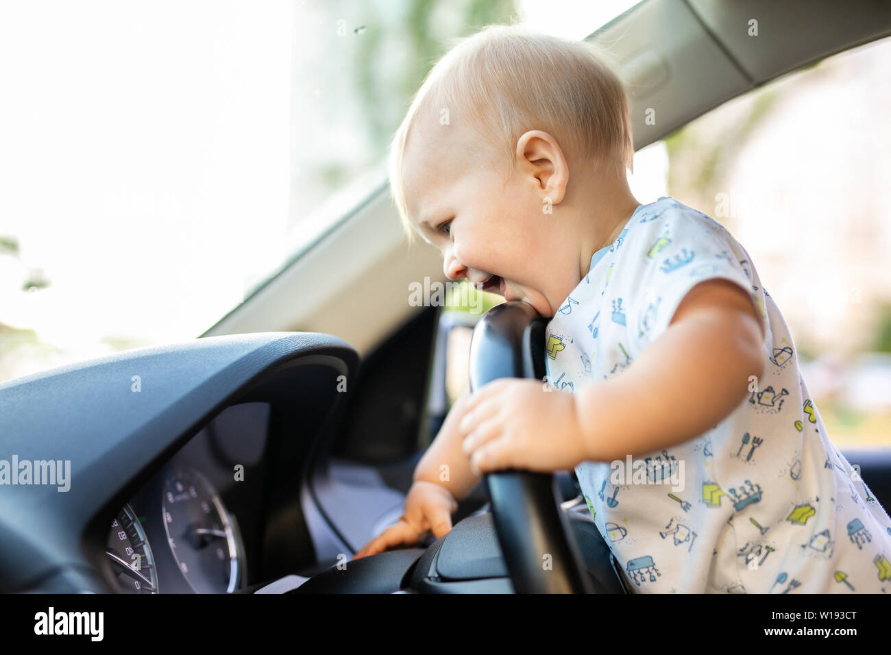 Cute little baby boy driving big car, holding steering wheel,smiling ...