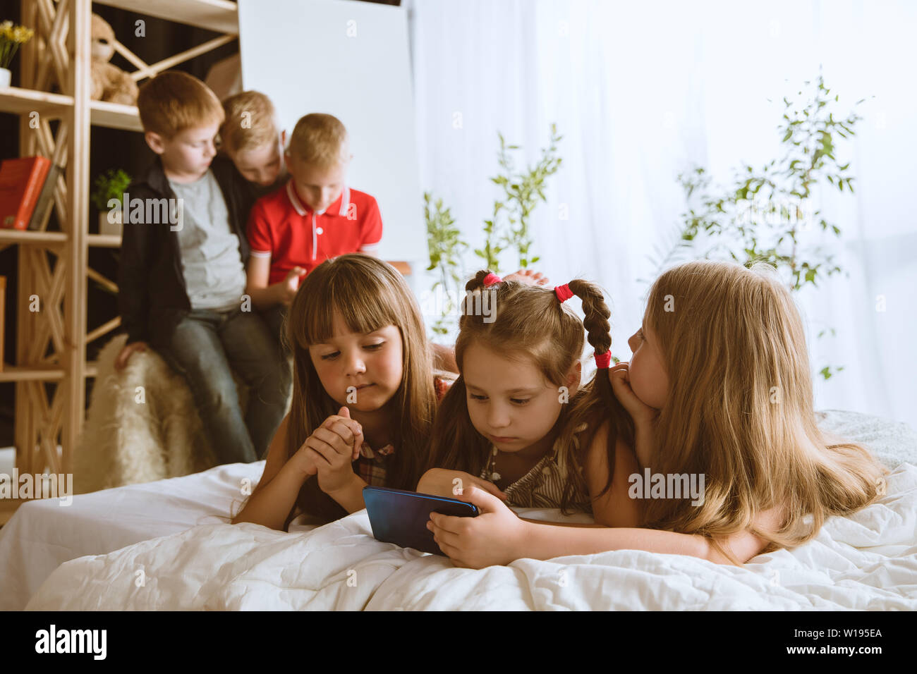 Boys and girls using different gadgets at home. Childs with smart ...