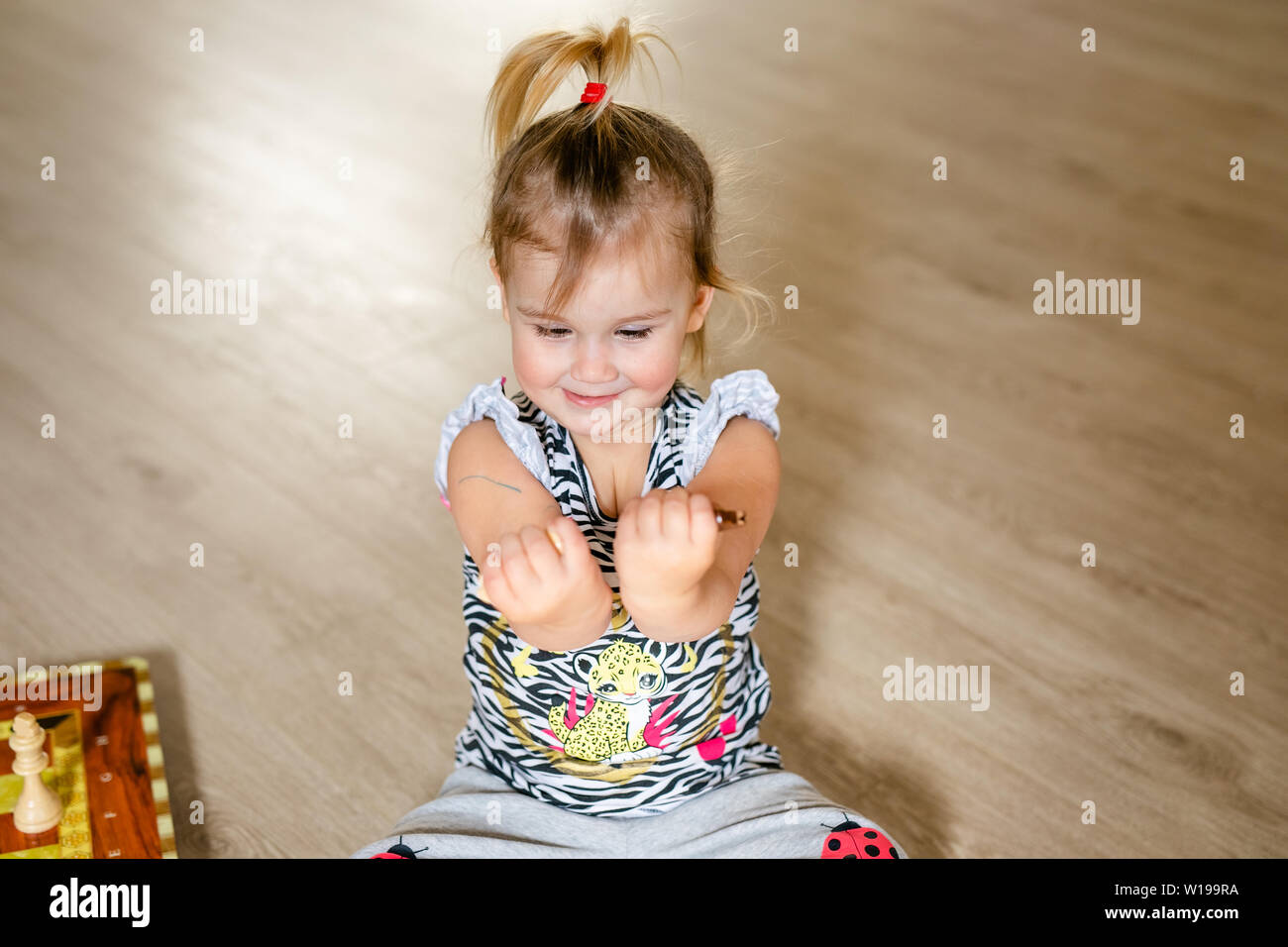 Two babies boy and girl playing chess on the white wooden floor at home ...