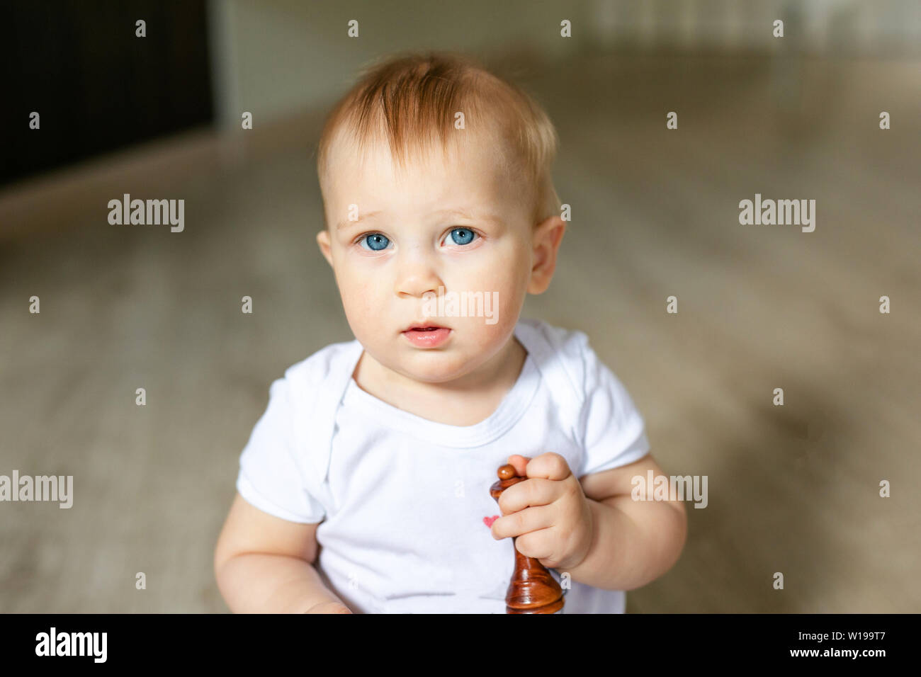 Two babies boy and girl playing chess on the white wooden floor at home ...