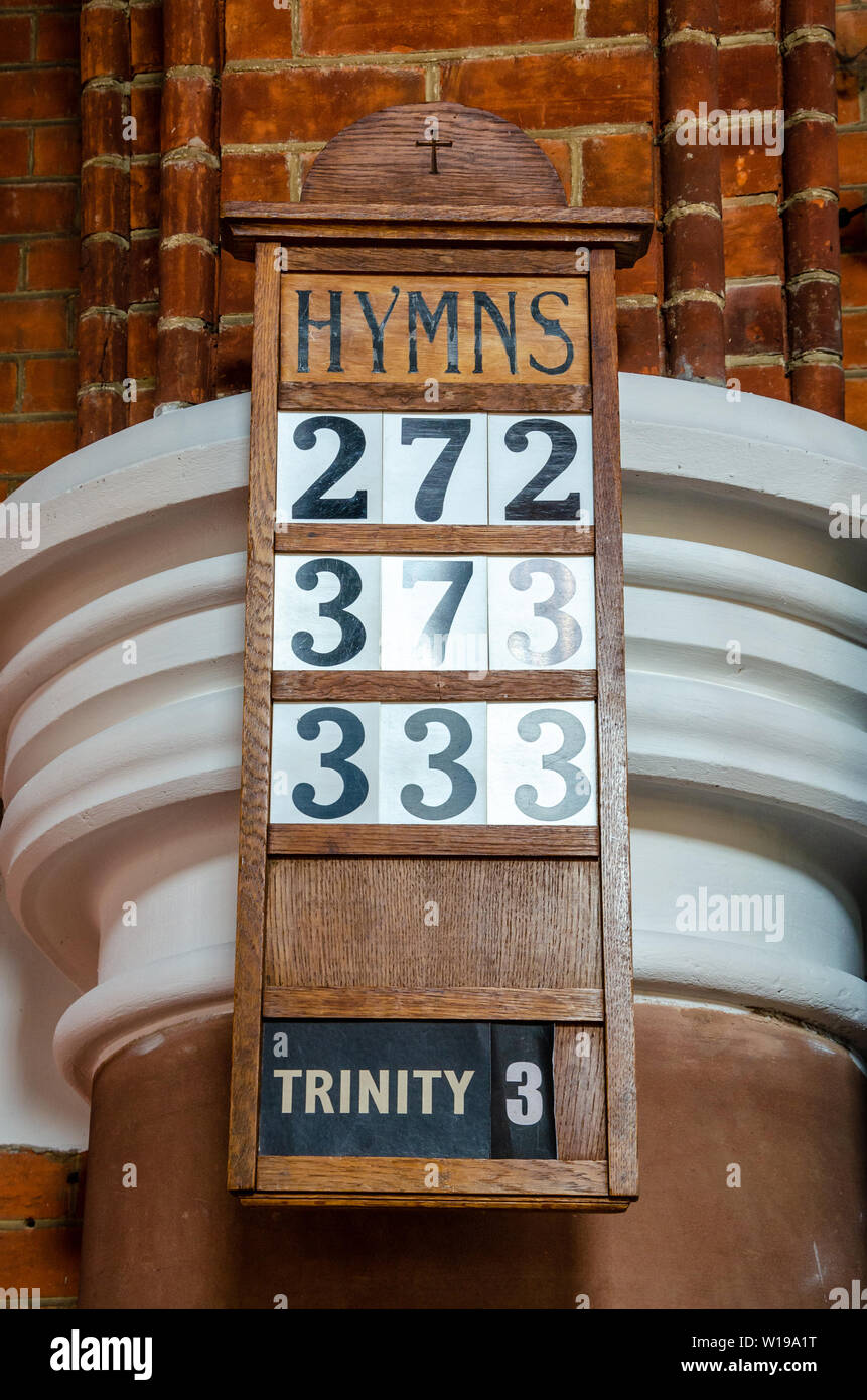 A wooden hymn board displaying hymn numbers attached to a column in a ...