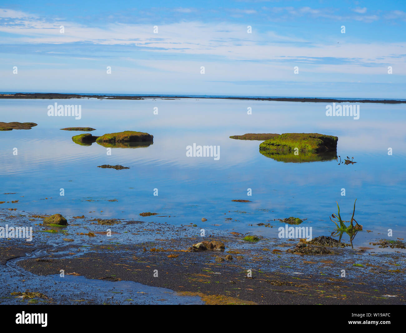View of rocks in the blue seawater from Seltjarnarnes peninsula ...