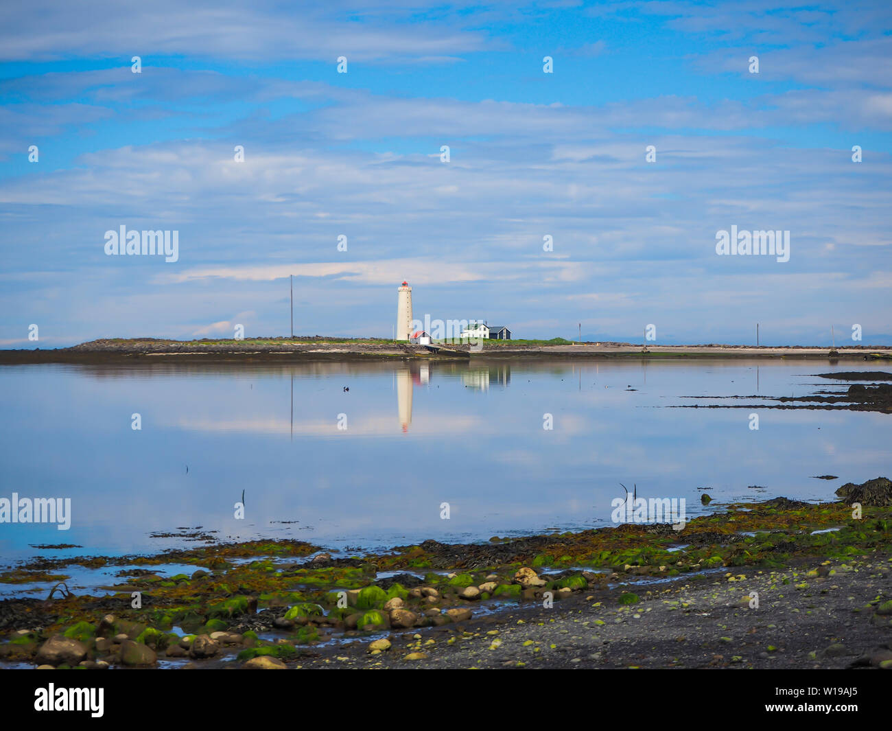 View of Grotta Lighthouse reflected in blue sea water from the ...