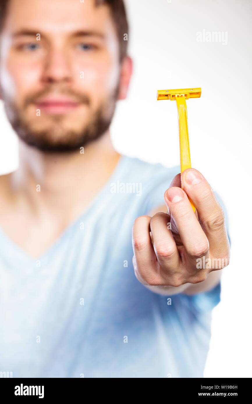 Young man guy with beard showing disposable yellow razor blade, studio ...