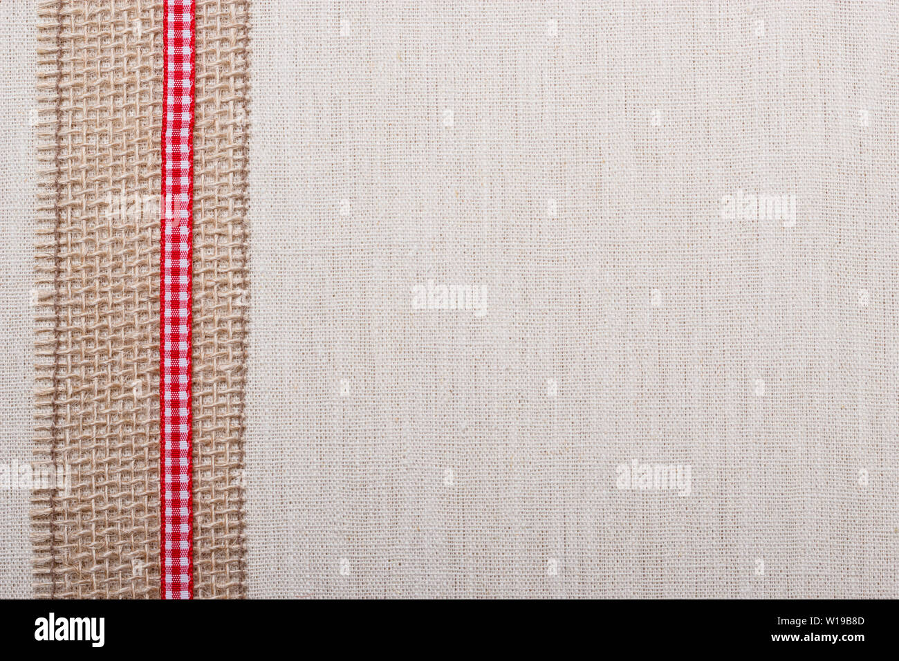 Jute mesh and red ribbon on bright fabric textile material, natural ...
