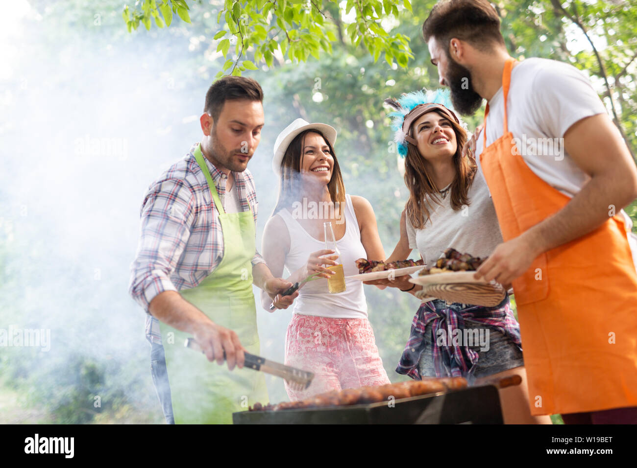 Friends having a barbecue party in nature while having fun Stock Photo ...