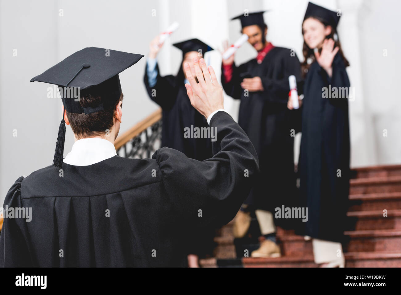 selective focus of student in graduation cap waving hand Stock Photo ...
