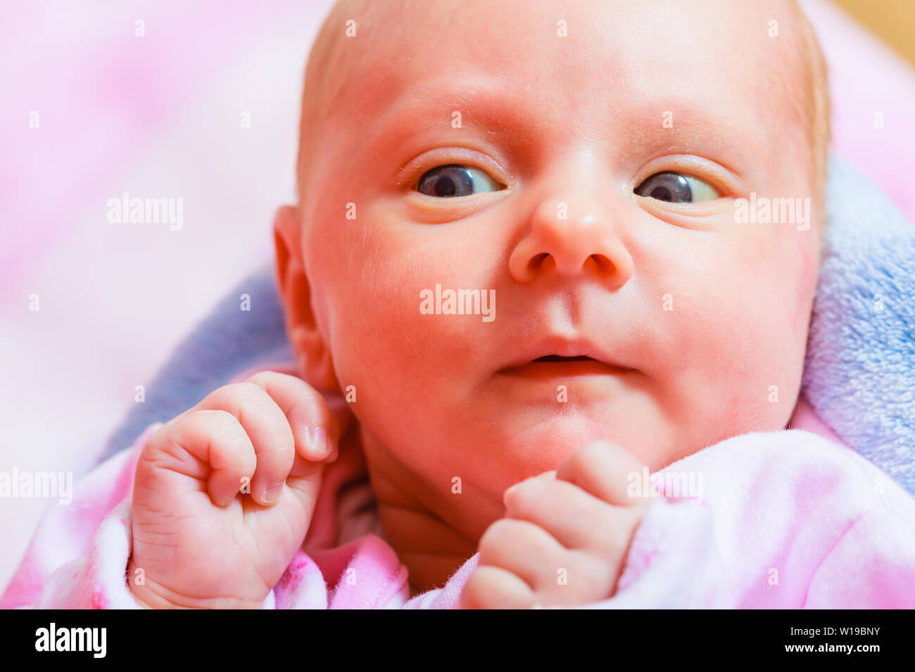 Little newborn baby in pyjamas lying on back. Face expression. Family ...
