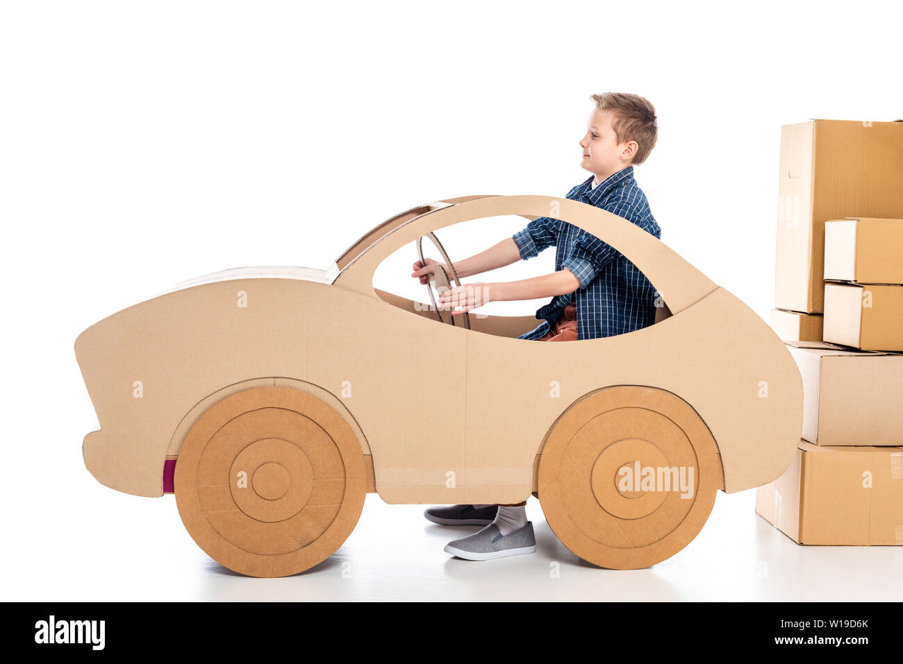 boy sitting in cardboard car and holding steering wheel on white Stock ...