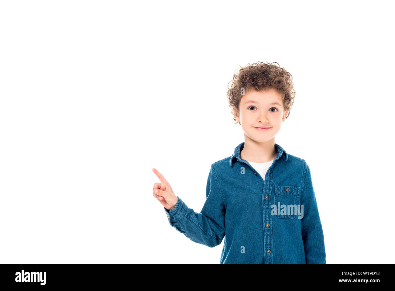 front view of smiling kid in denim shirt pointing with finger isolated ...