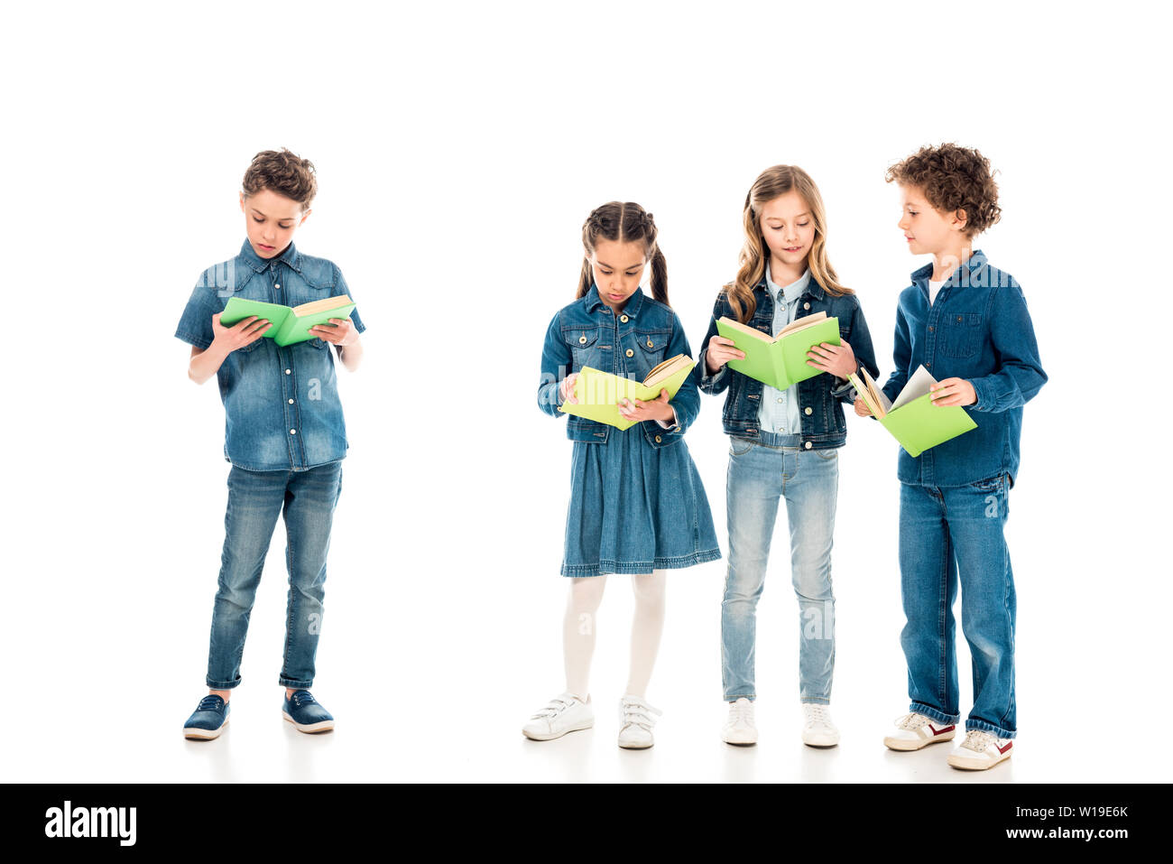 full length view of four concentrated kids reading books on white Stock ...