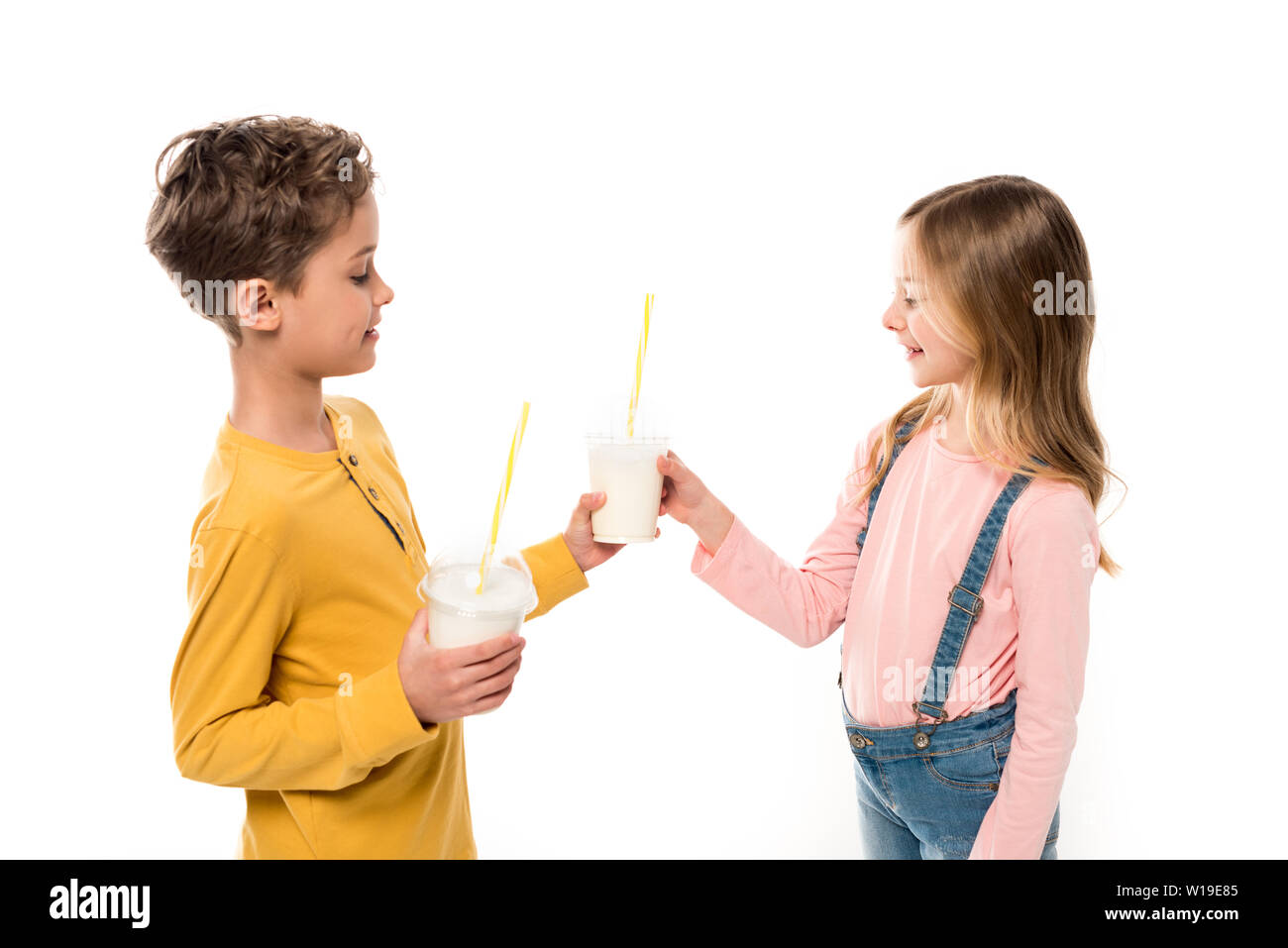 two smiling kids holding milkshakes isolated on white Stock Photo - Alamy