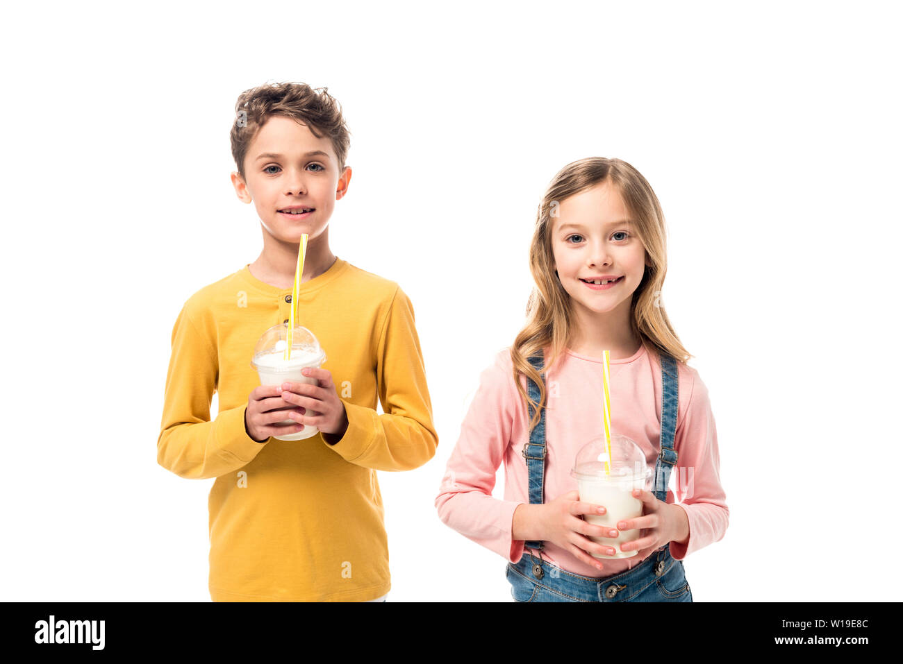 two smiling kids holding milkshakes isolated on white Stock Photo - Alamy