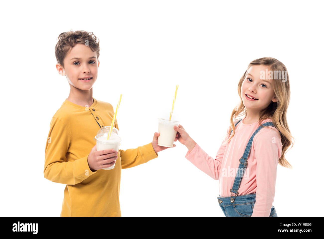 two smiling kids holding milkshakes isolated on white Stock Photo - Alamy