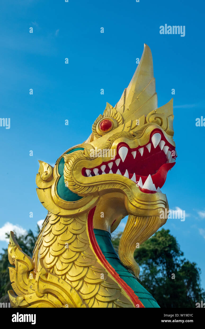 A close up of ornate green, gold and red naga statue in front of the ...