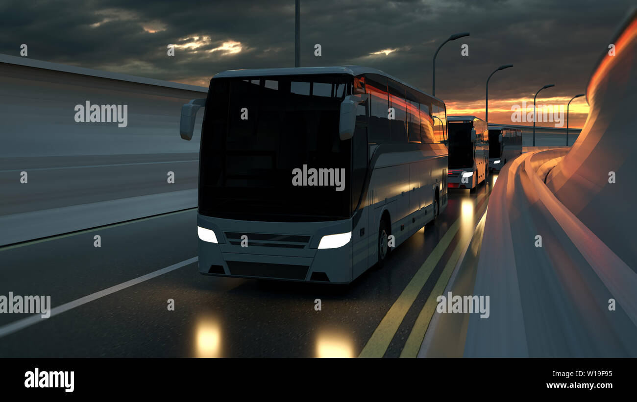 A convoy of three white buses drive on a highway at sunset backlit by a ...