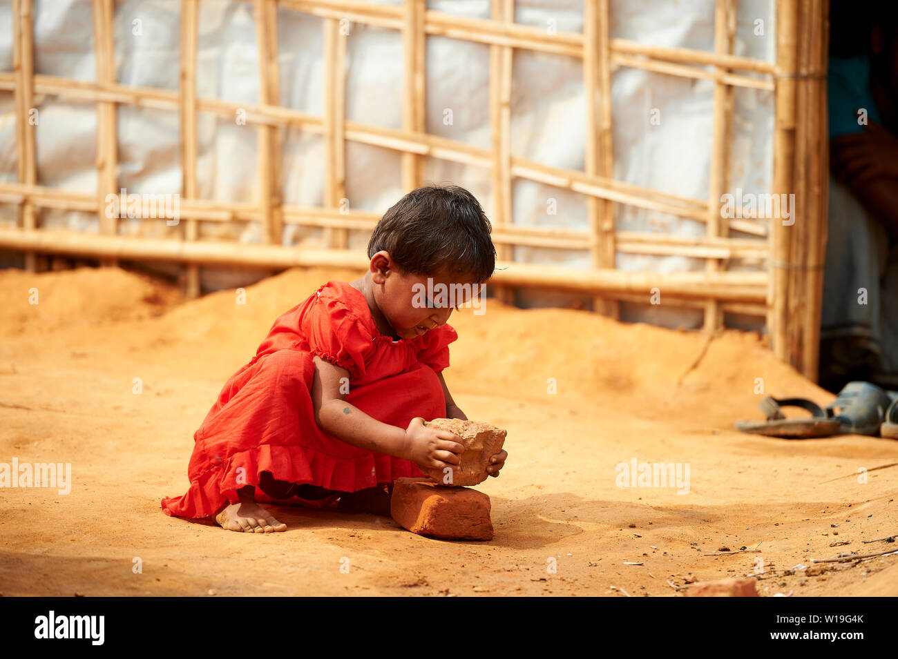 Child in red dress breaking nuts in Rohingya Refugee Camp Kutupalong ...
