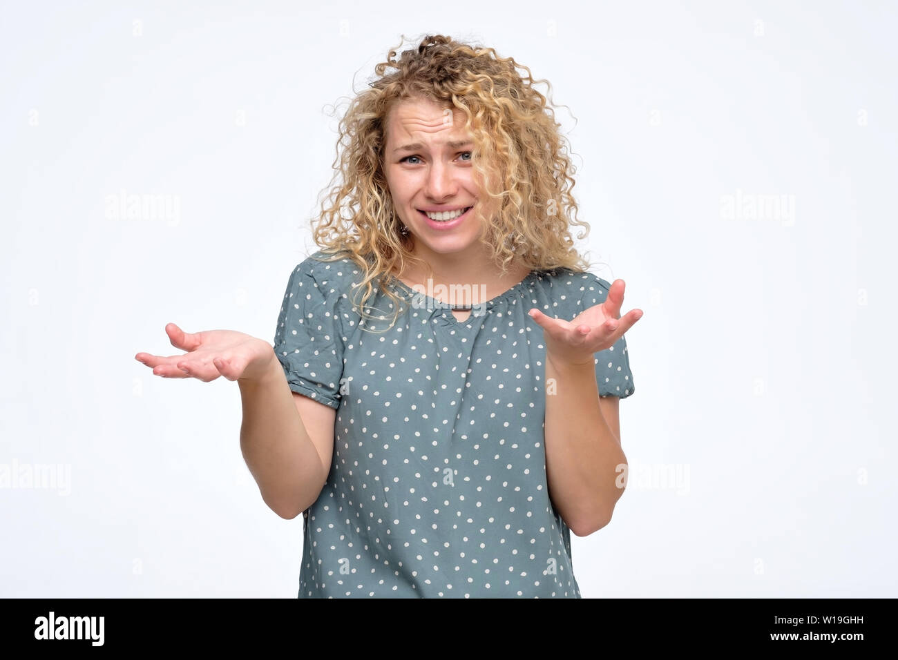 Woman has displeased expression shrugging her shoulders Stock Photo - Alamy
