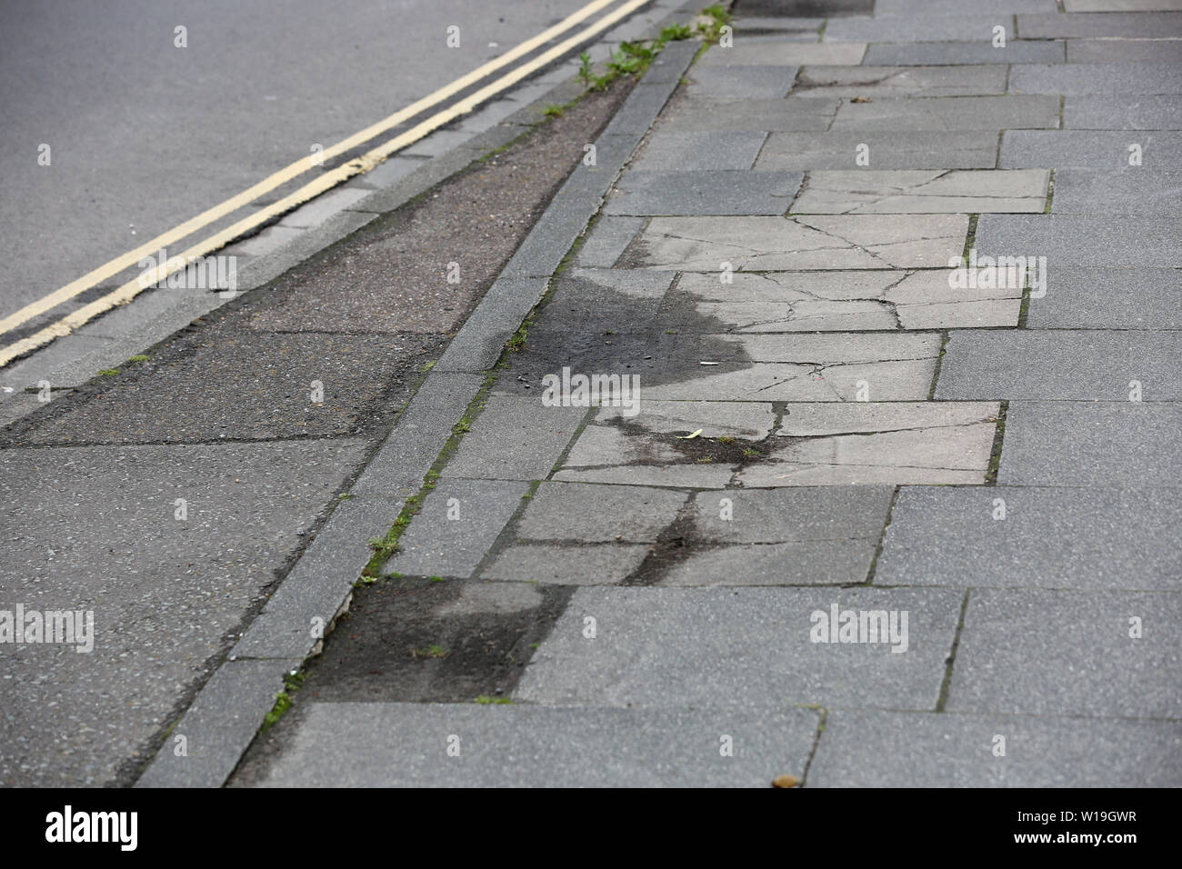Pot holes and damaged concrete slabs on a path in Chichester, West ...