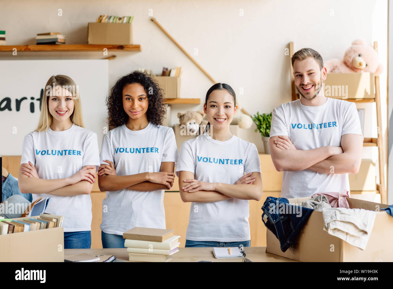 four smiling young volunteers in white t-shirts with volunteer ...
