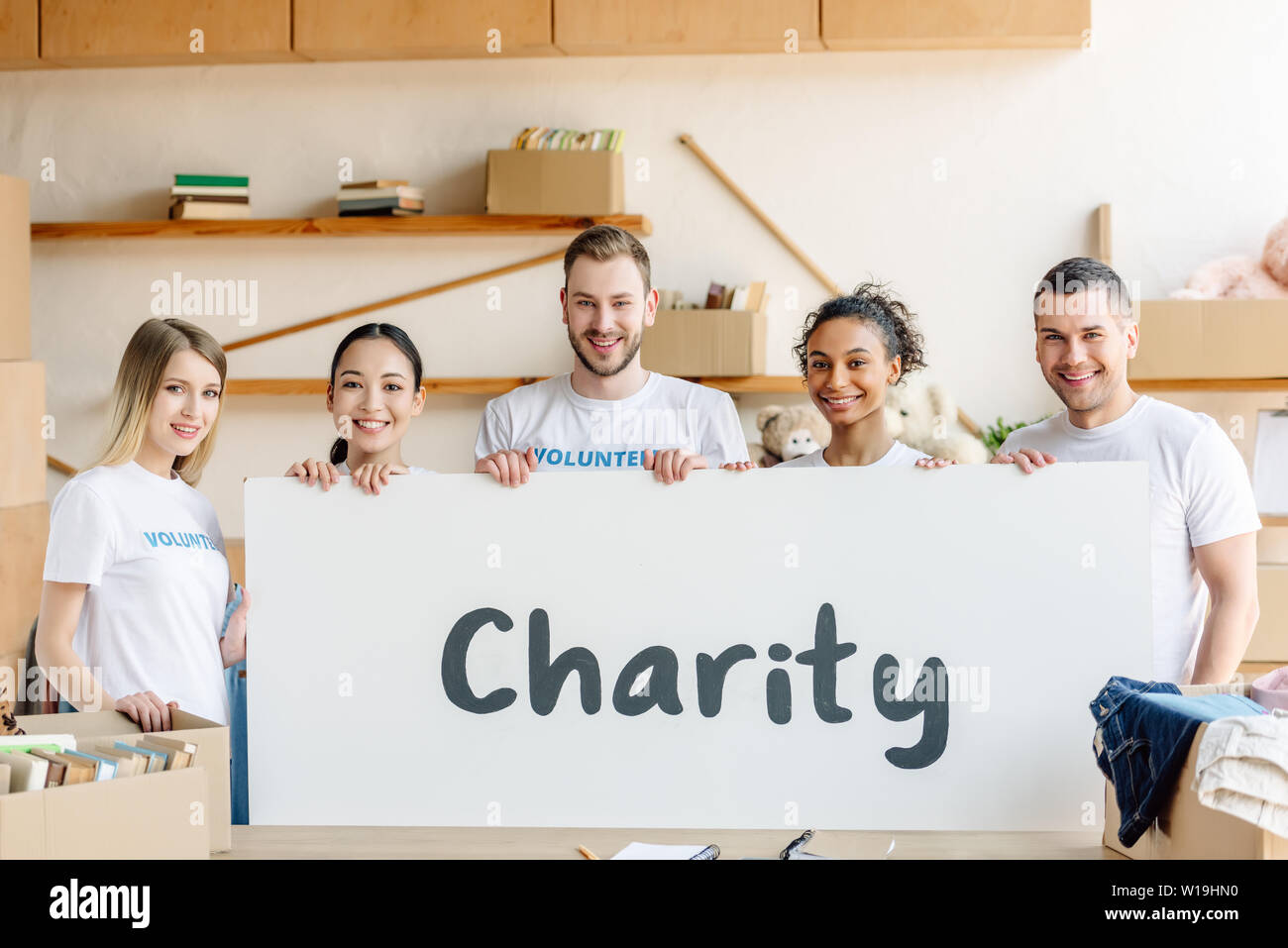 five young, multicultural volunteers holding placard with charity ...