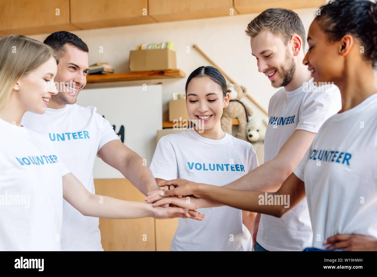 five young multicultural volunteers smiling and holding hands in ...