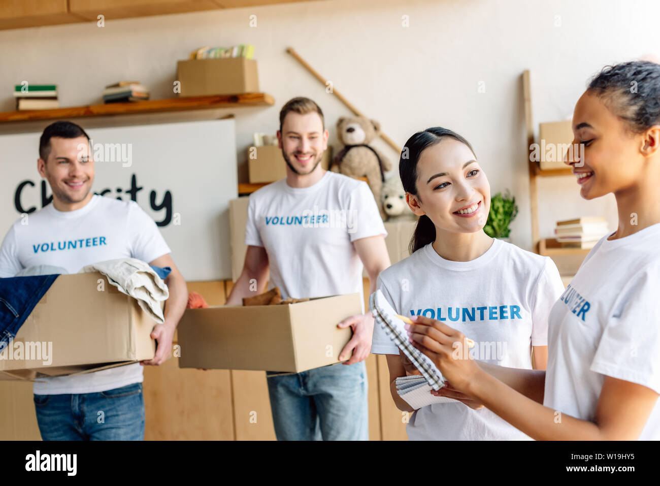 selective focus of cheerful, multicultural volunteers working in ...