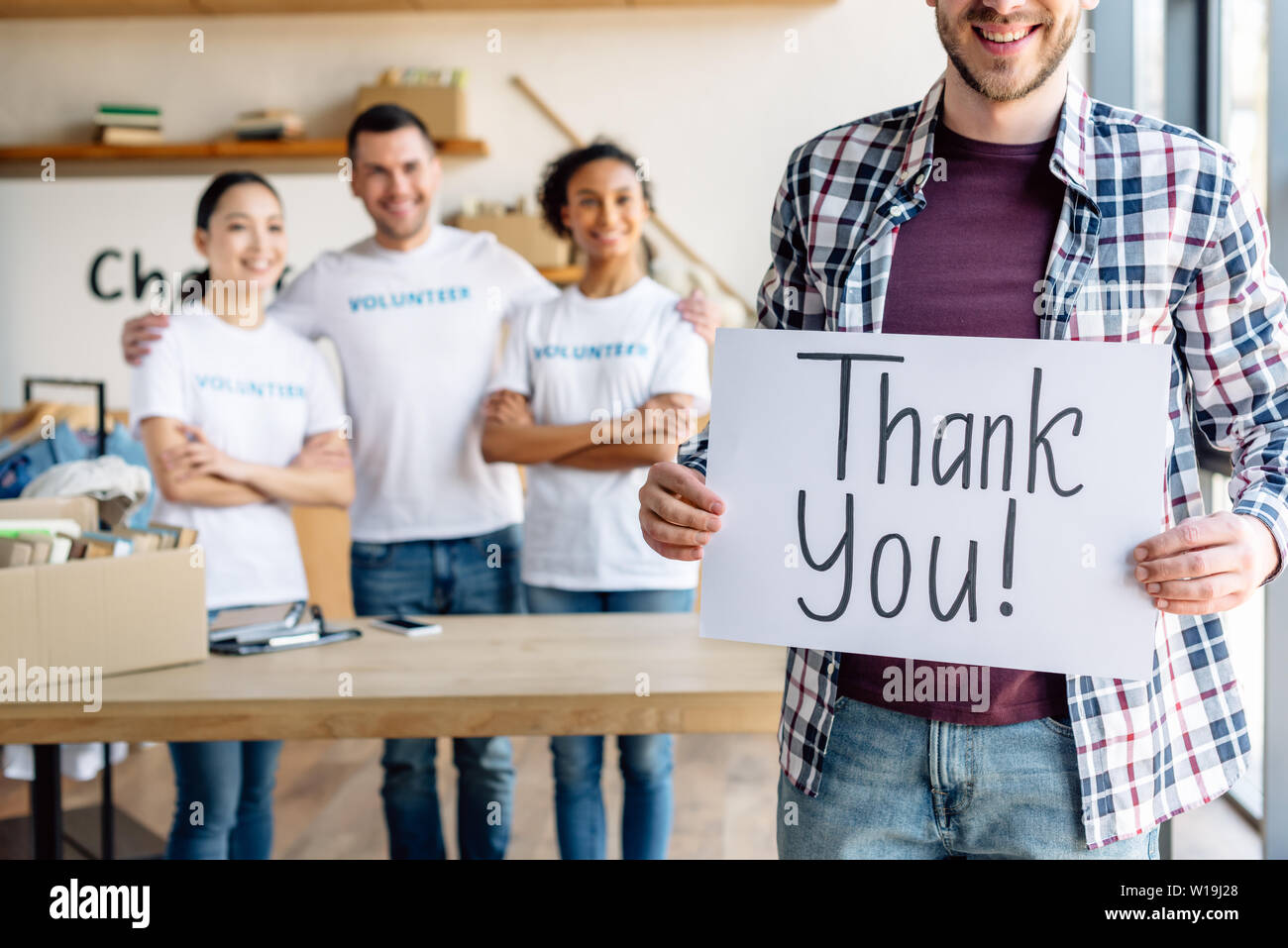 partial view of man holding card with thank you text while standing ...