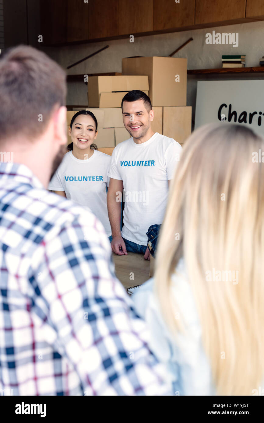 selective focus of smiling multicultural volunteers meeting people in ...