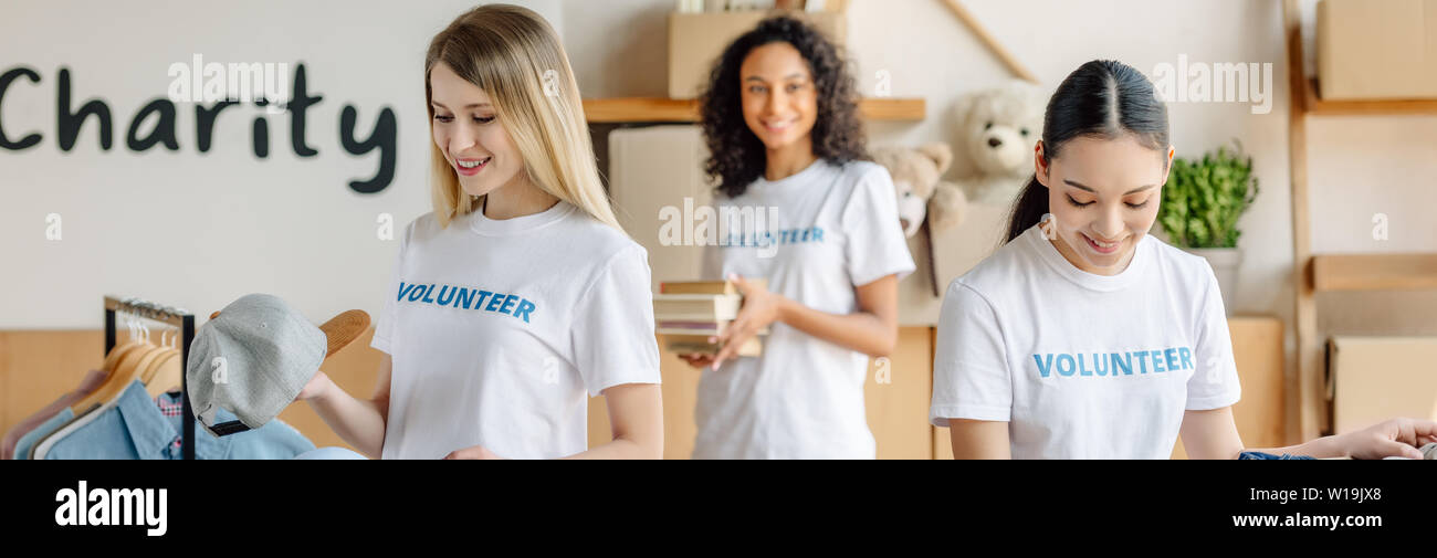 panoramic shot of three beautiful multicultural volunteers working in ...