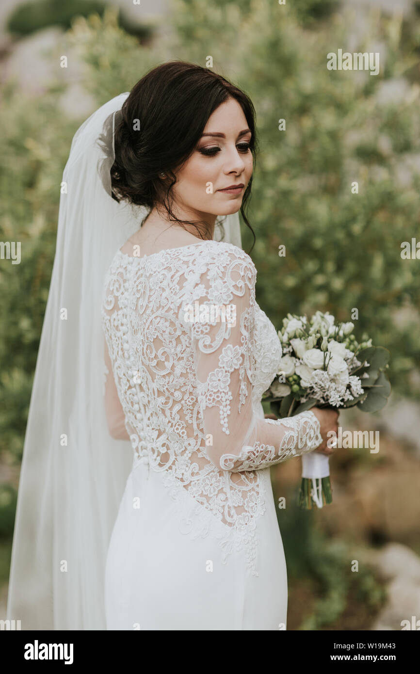 Bride holding wedding bouquet. Portrait of young bride wearing elegant ...