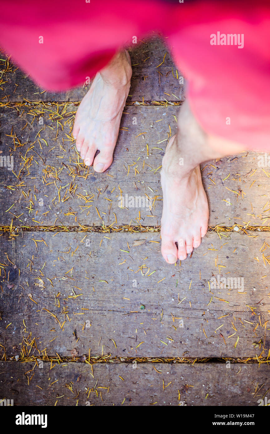 Barefoot feet on a rusty old wooden bridge in the forest, adventure ...