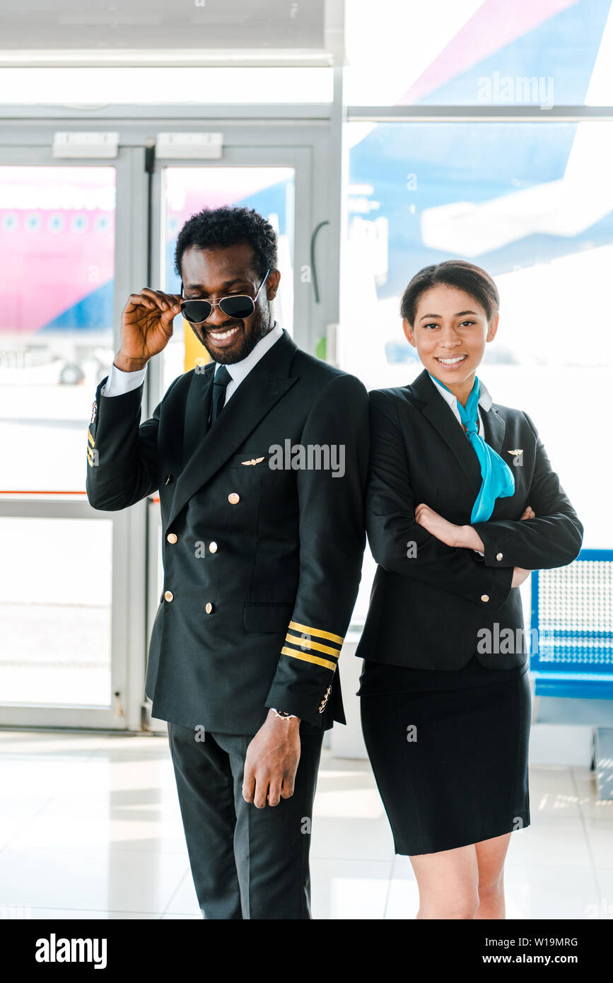 african american pilot in sunglasses and stewardess with crossed arms ...