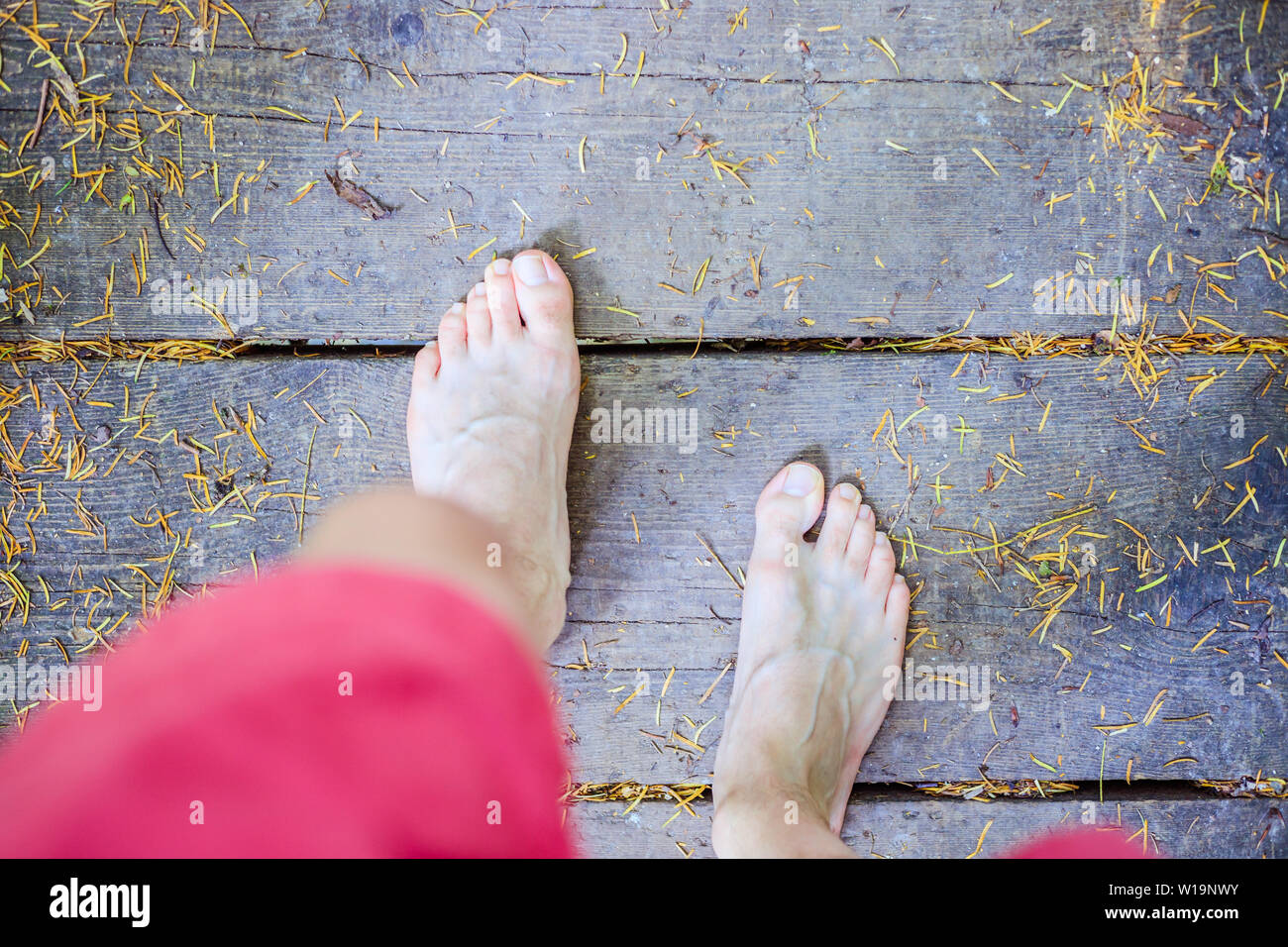 Barefoot feet on a rusty old wooden bridge in the forest, adventure ...
