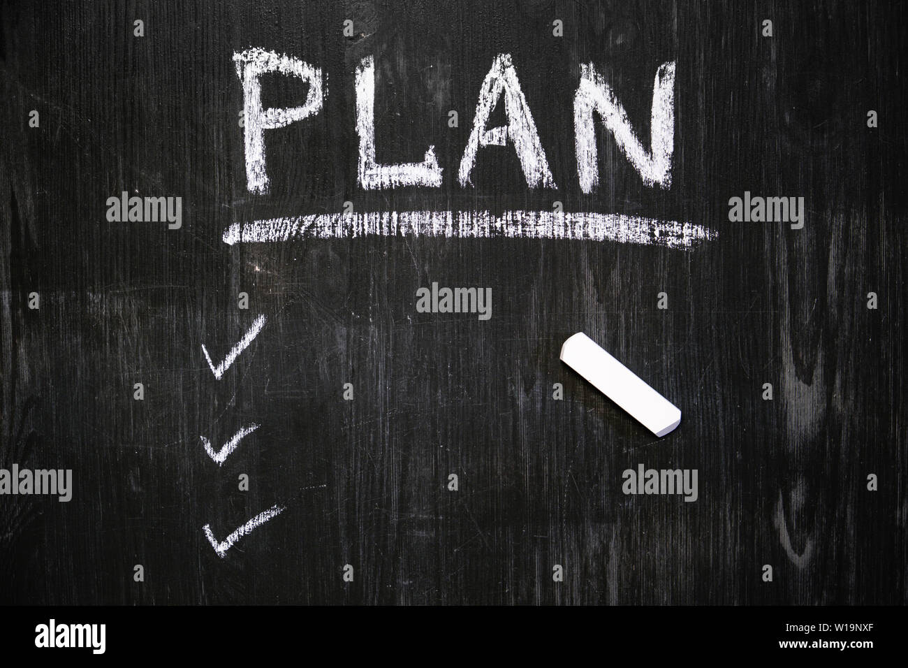 Plan word handwritten with chalk on blackboard. Black wood background ...