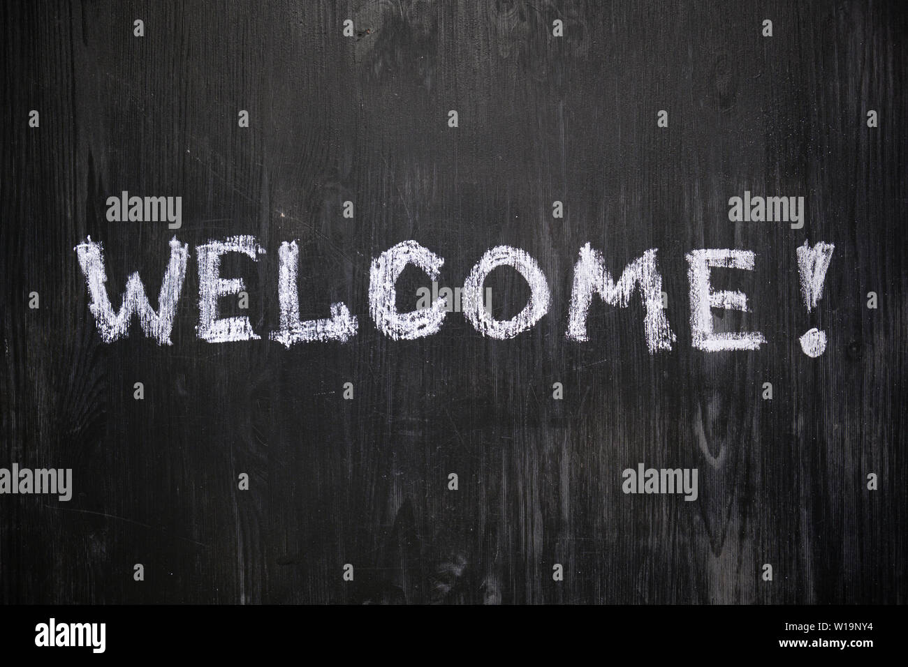 Welcome sign handwritten on black background. The word "welcome ...