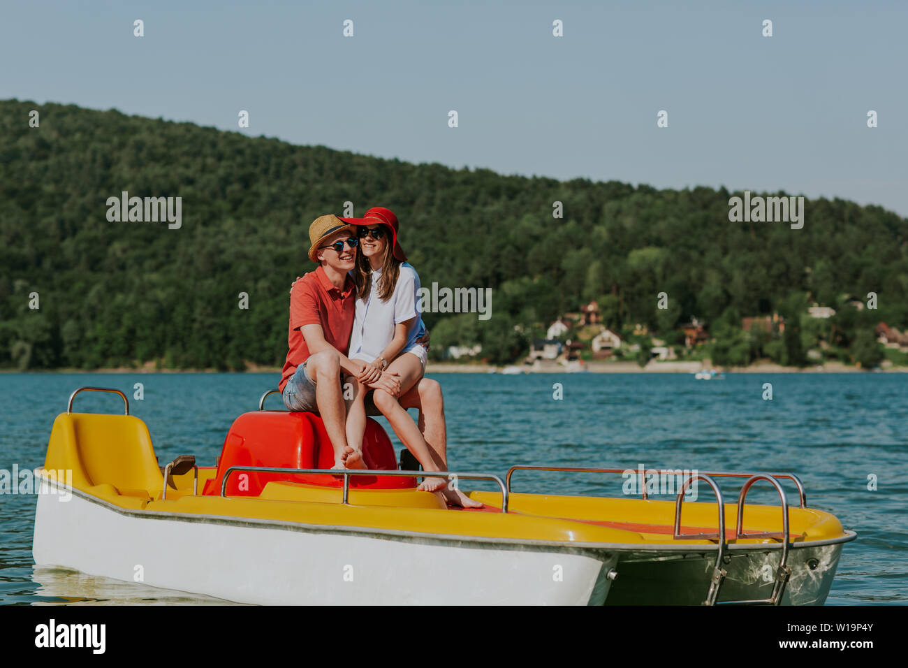 Young lovers having fun in pedalo boat on hot summer day. Cheerful man ...