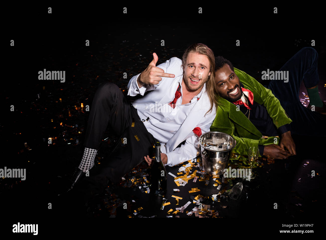 happy and drunk man showing middle finger while sitting near african ...