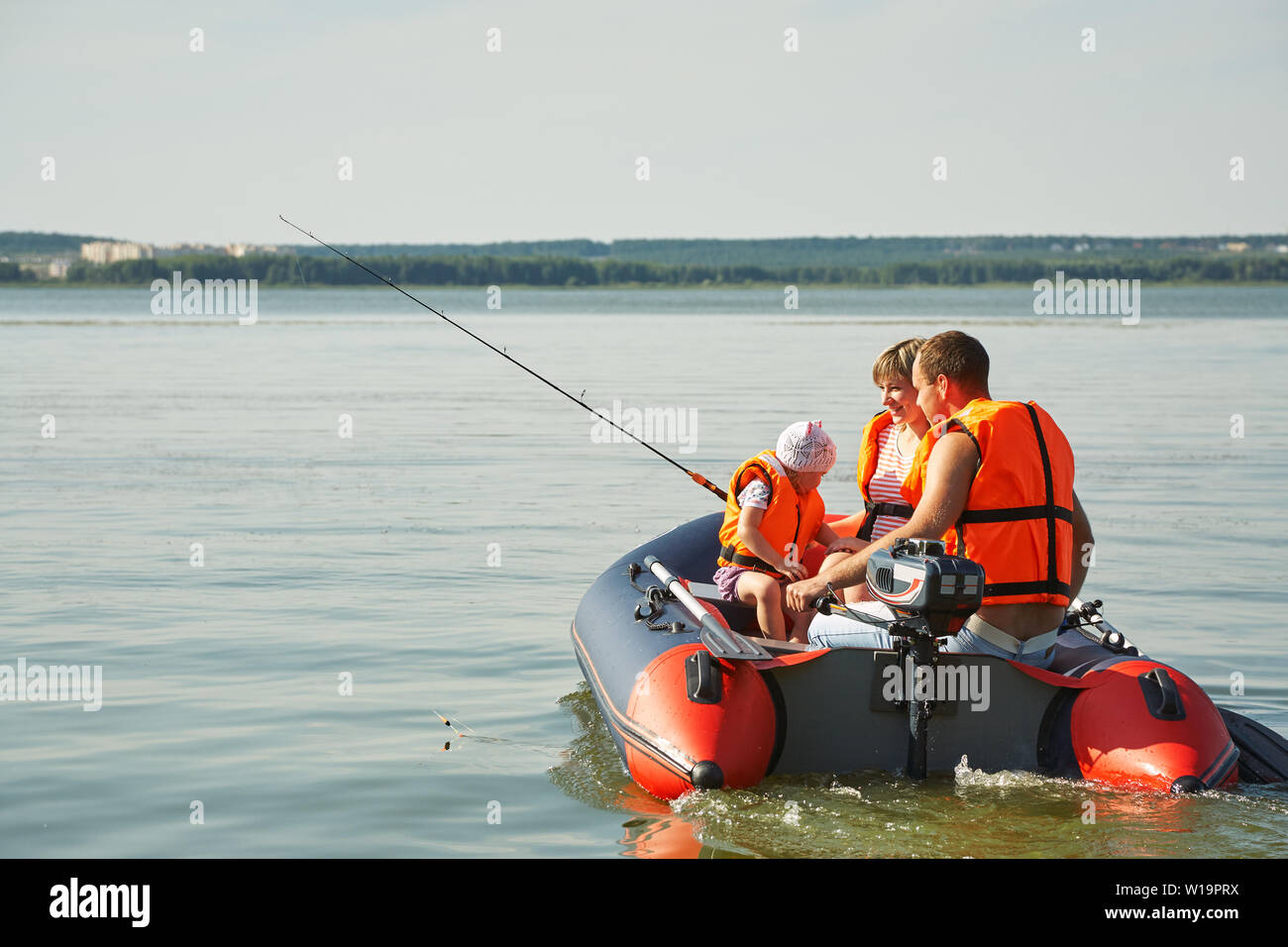 family fishing in a boat on the river. parents with child resting ...