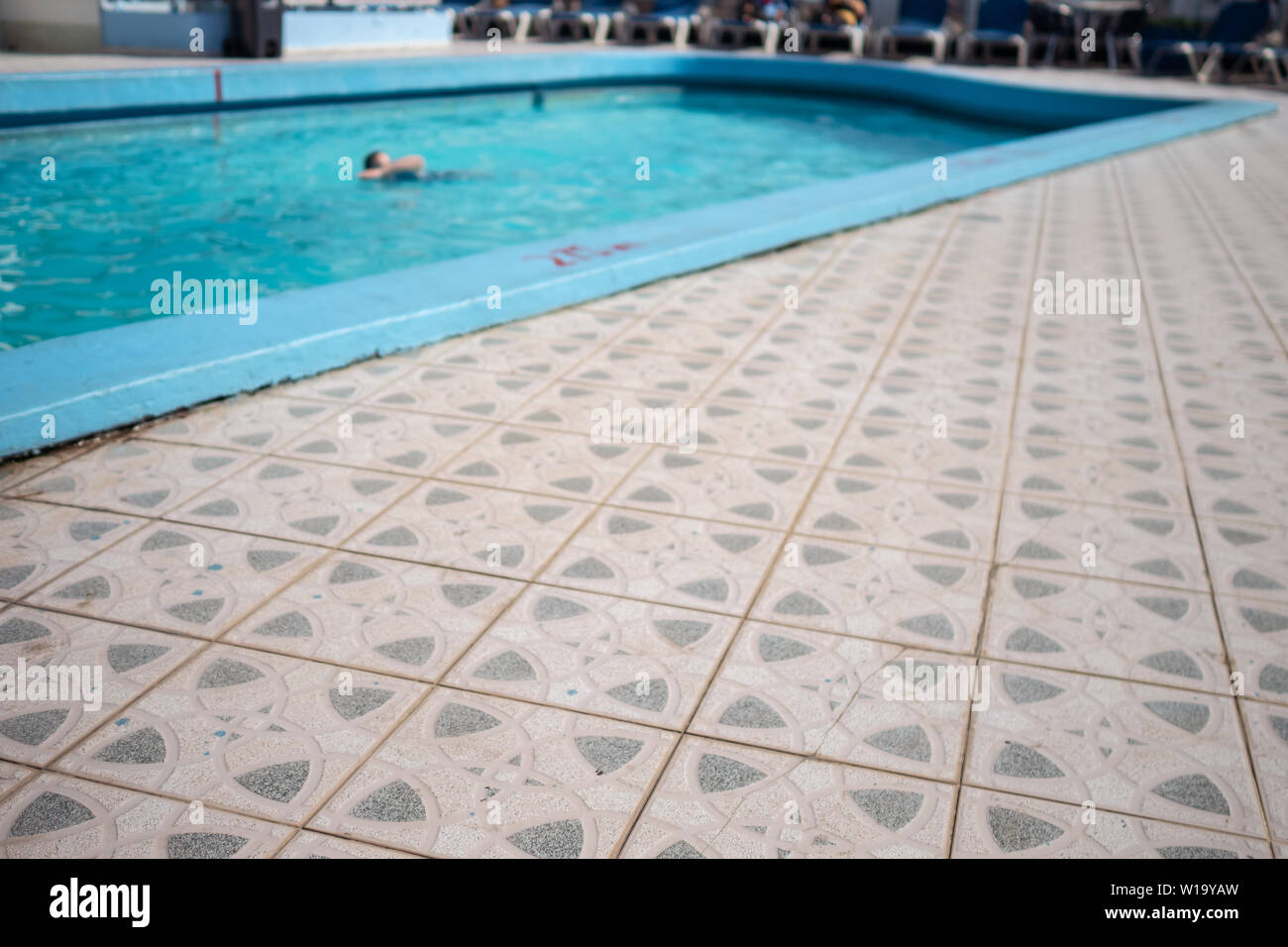Tiled poolside and swimmer in the background Stock Photo - Alamy