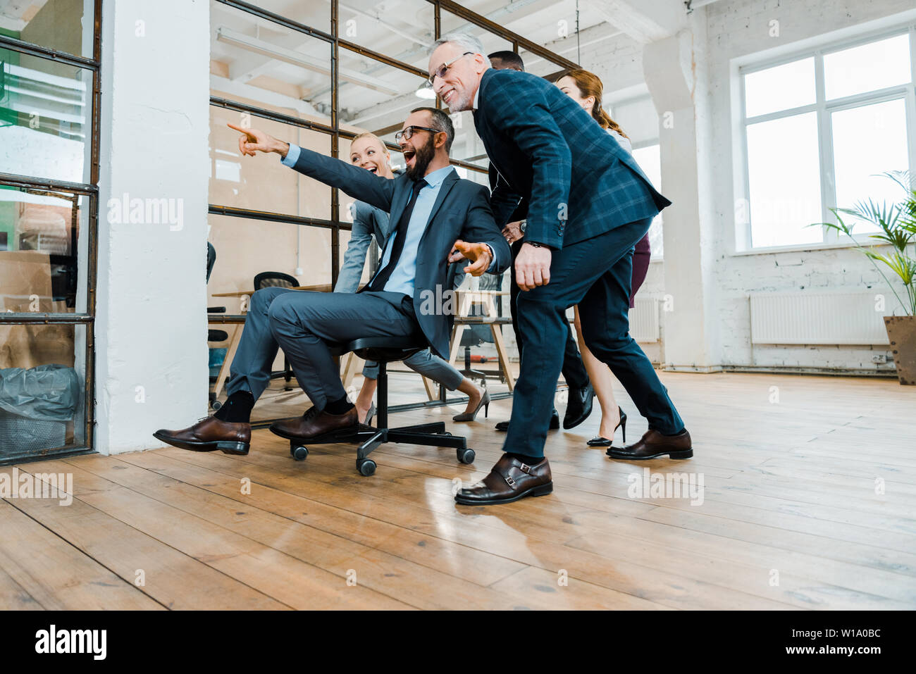 low angle view of cheerful businessman sitting on chair and pointing ...