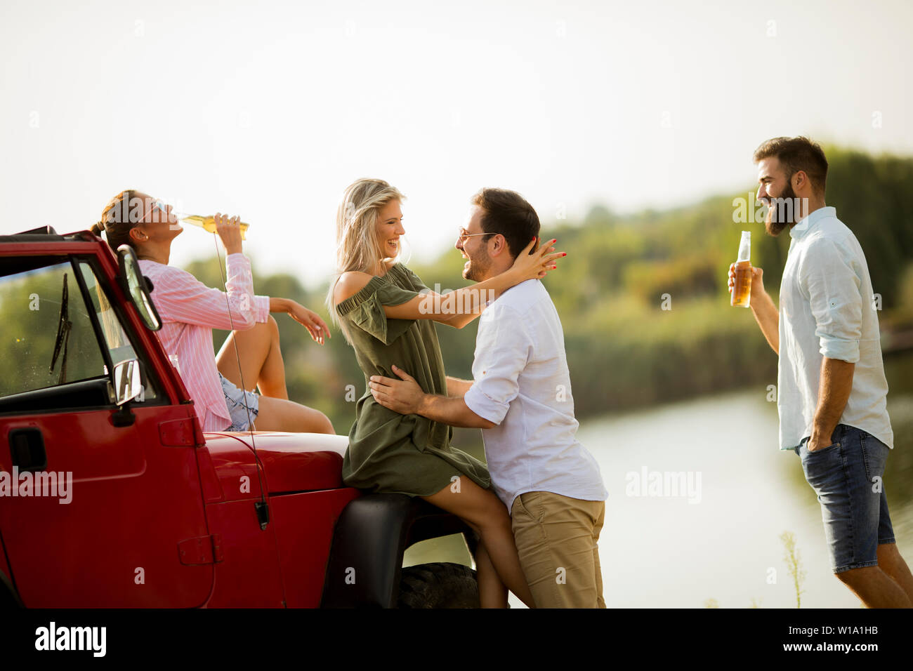 Four young people having fun in convertible car by river Stock Photo ...