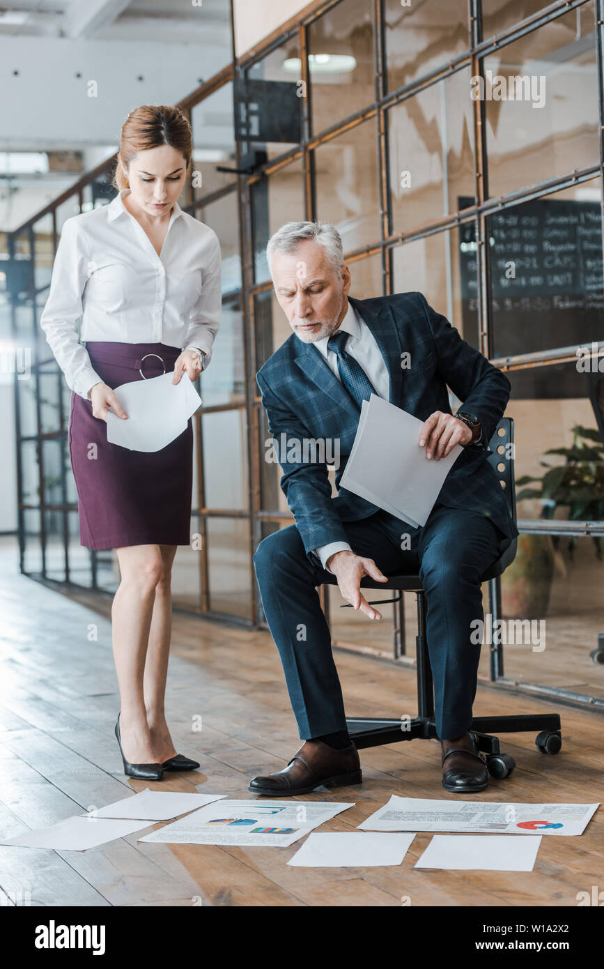 handsome man pointing with finger at charts and graphs while sitting on ...
