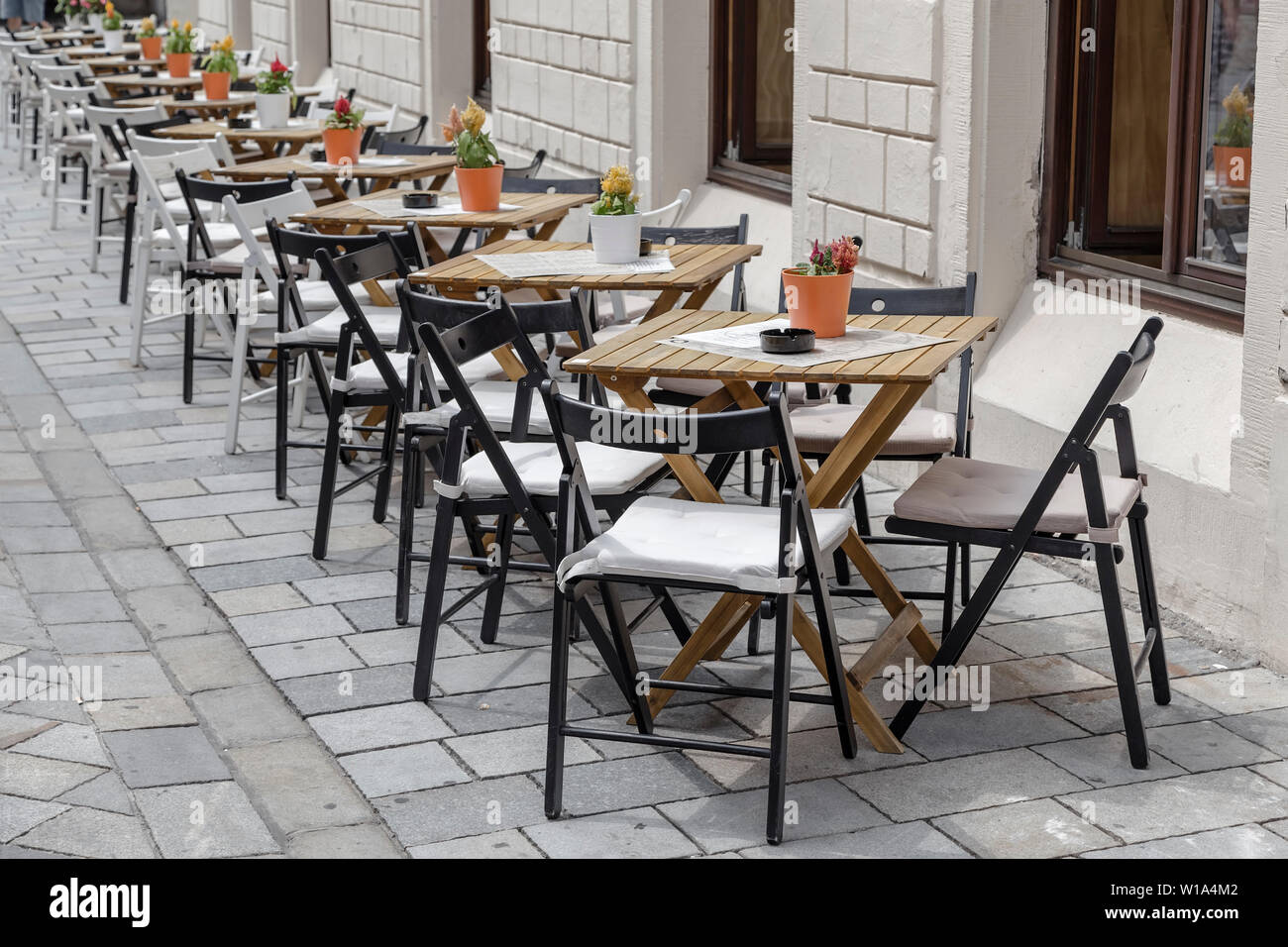 Tables and chairs in a row along the wall there are cafes in the street ...