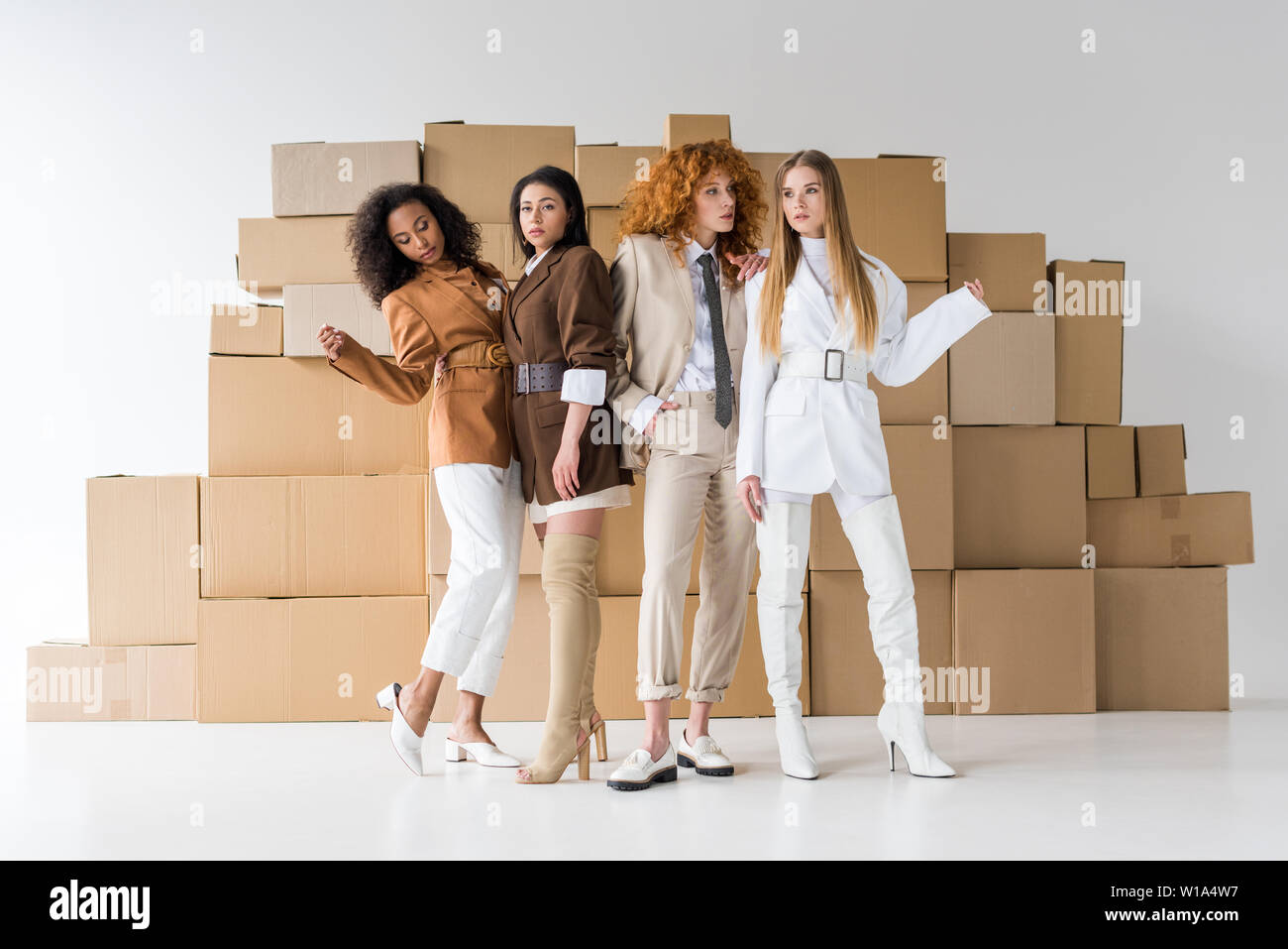 pretty young multicultural women posing near boxes on white Stock Photo ...