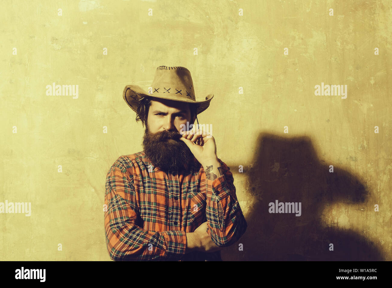 Bearded man in cowboy hat and black shadow on wall Stock Photo - Alamy