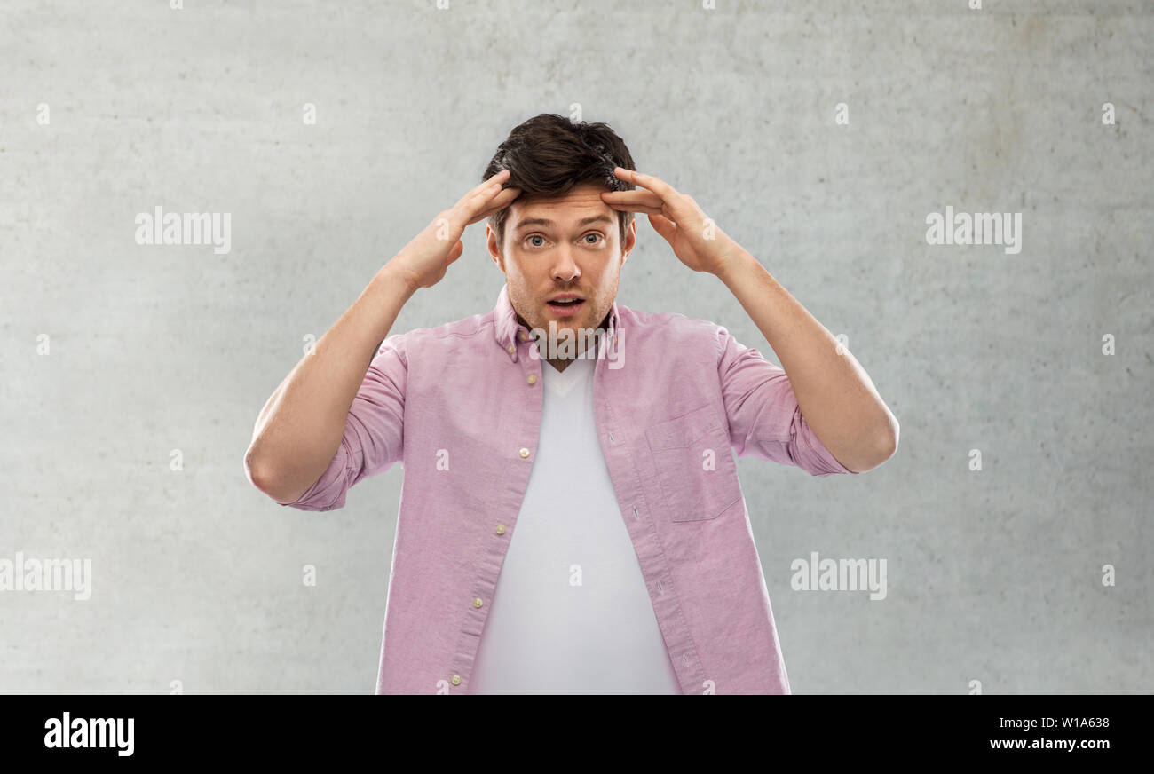 man touching his head over grey concrete wall Stock Photo - Alamy